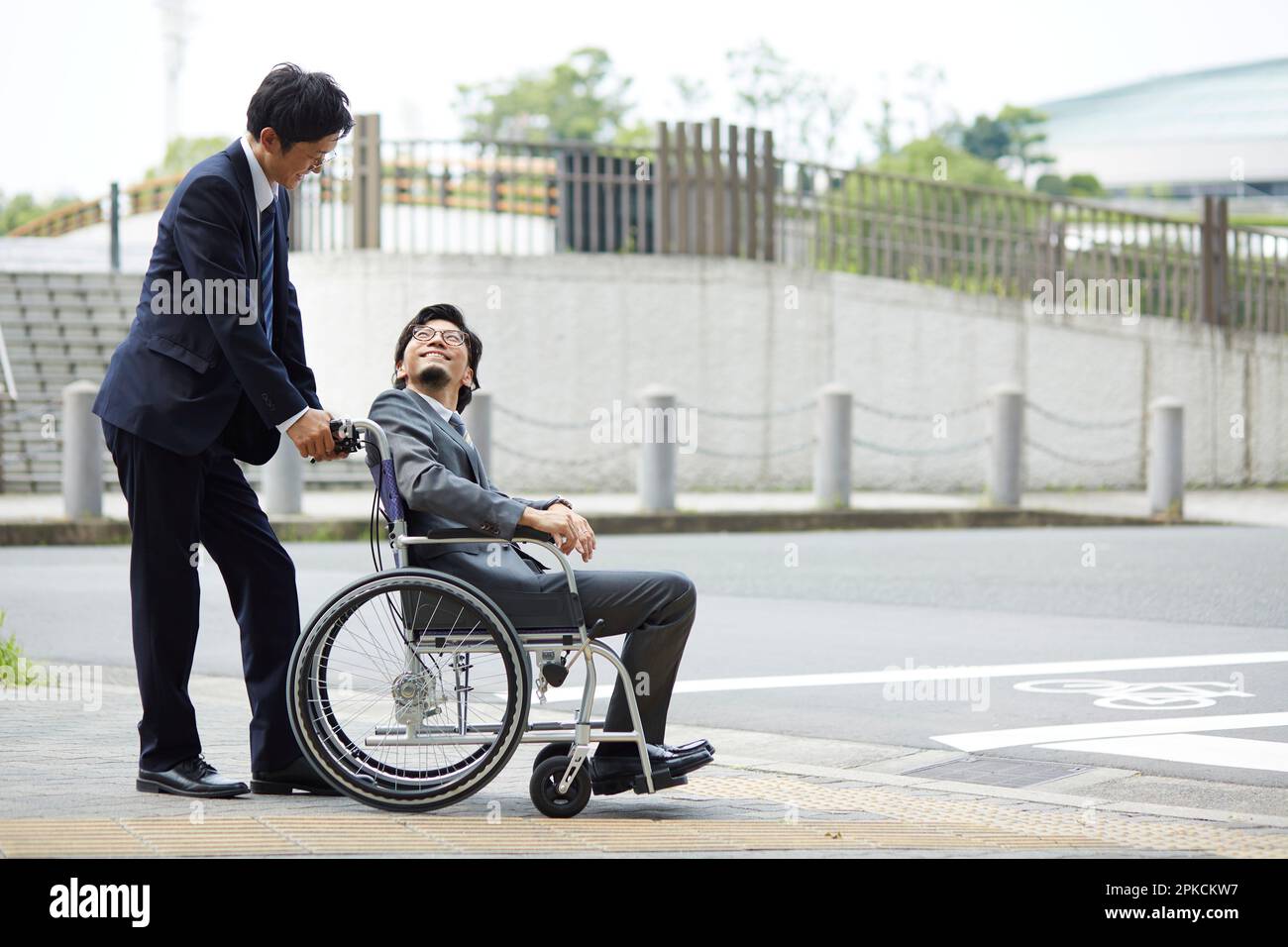 Man in suit pushing man in wheelchair Stock Photo - Alamy