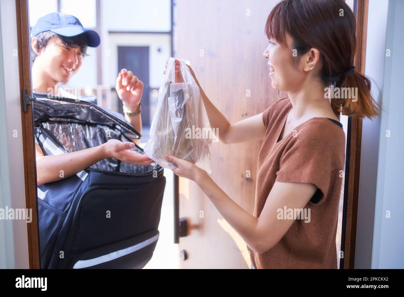 Woman receiving items from food delivery man Stock Photo - Alamy