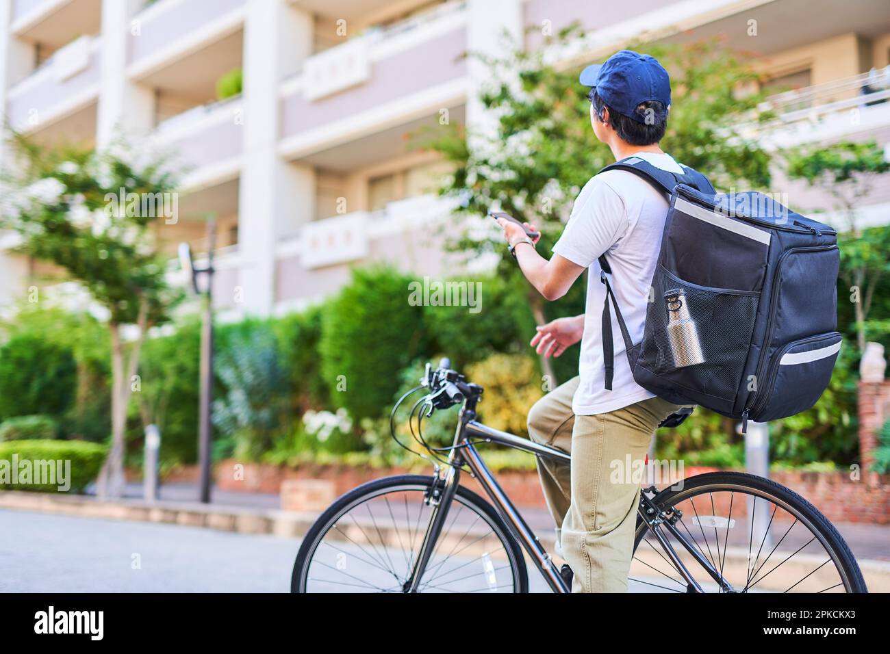Back view of food delivery man with cell phone Stock Photo - Alamy