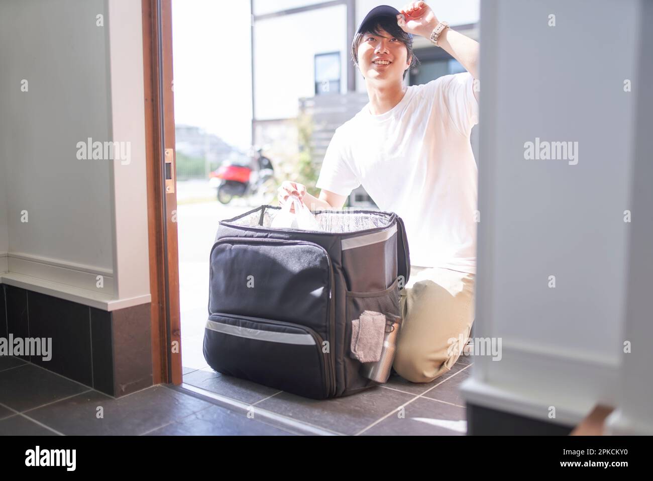 Food delivery man taking items out of backpack at front door Stock ...