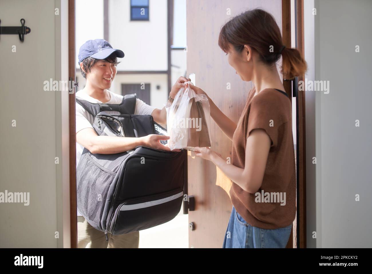 Woman receiving items from food delivery delivery man Stock Photo - Alamy