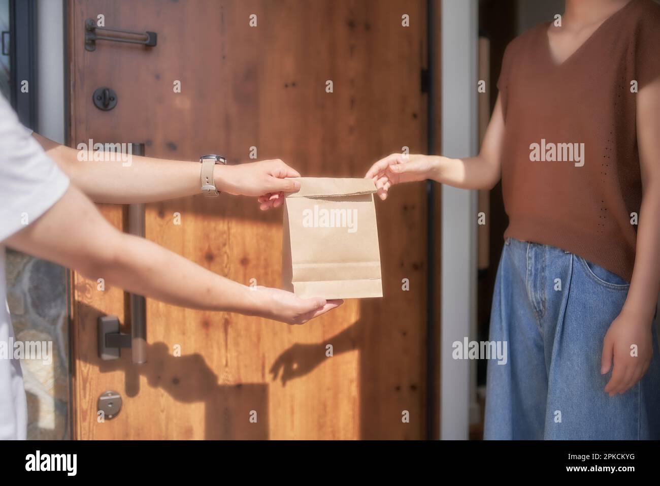 Woman receiving items from food delivery delivery man Stock Photo - Alamy