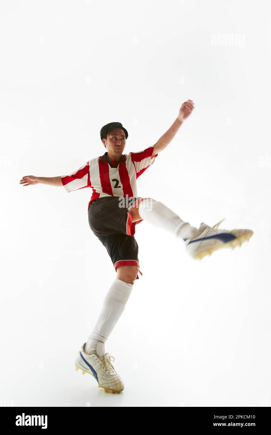 Soccer player kicking a ball and swinging his leg Stock Photo - Alamy