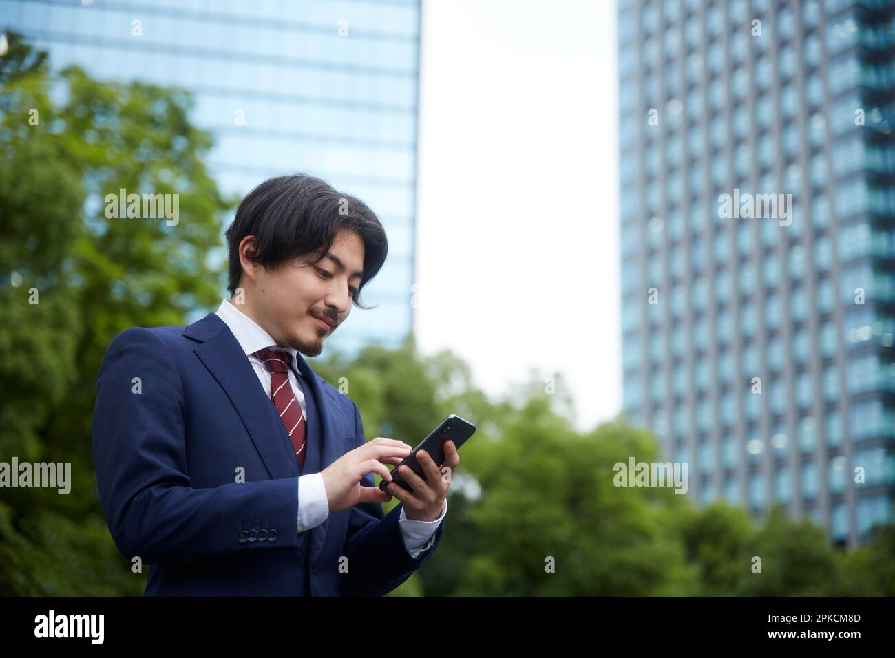 Man in suit operating smartphone with background of building Stock ...