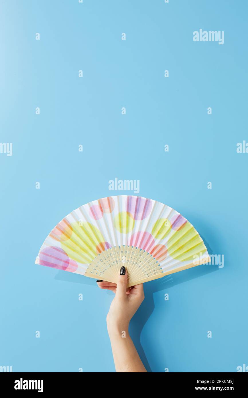 Woman's hand holding fan on light blue background Stock Photo - Alamy