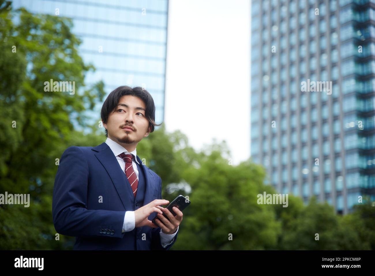 Man in suit operating smartphone with background of building Stock ...