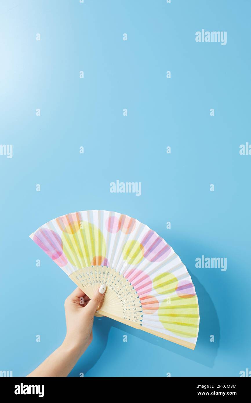 Woman's hand with fan on light blue background Stock Photo - Alamy