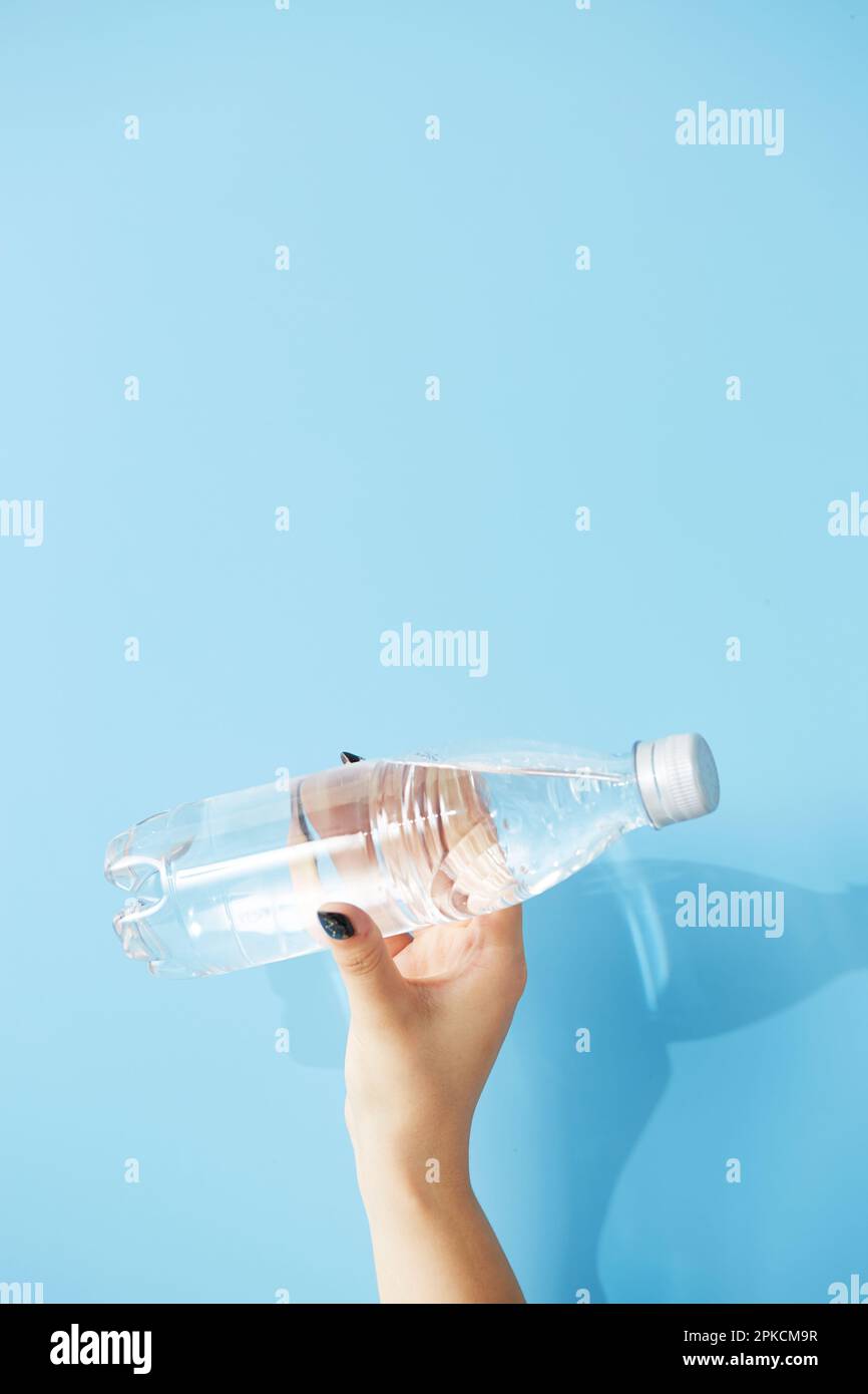 Woman's hand with plastic bottle on light blue background Stock Photo ...