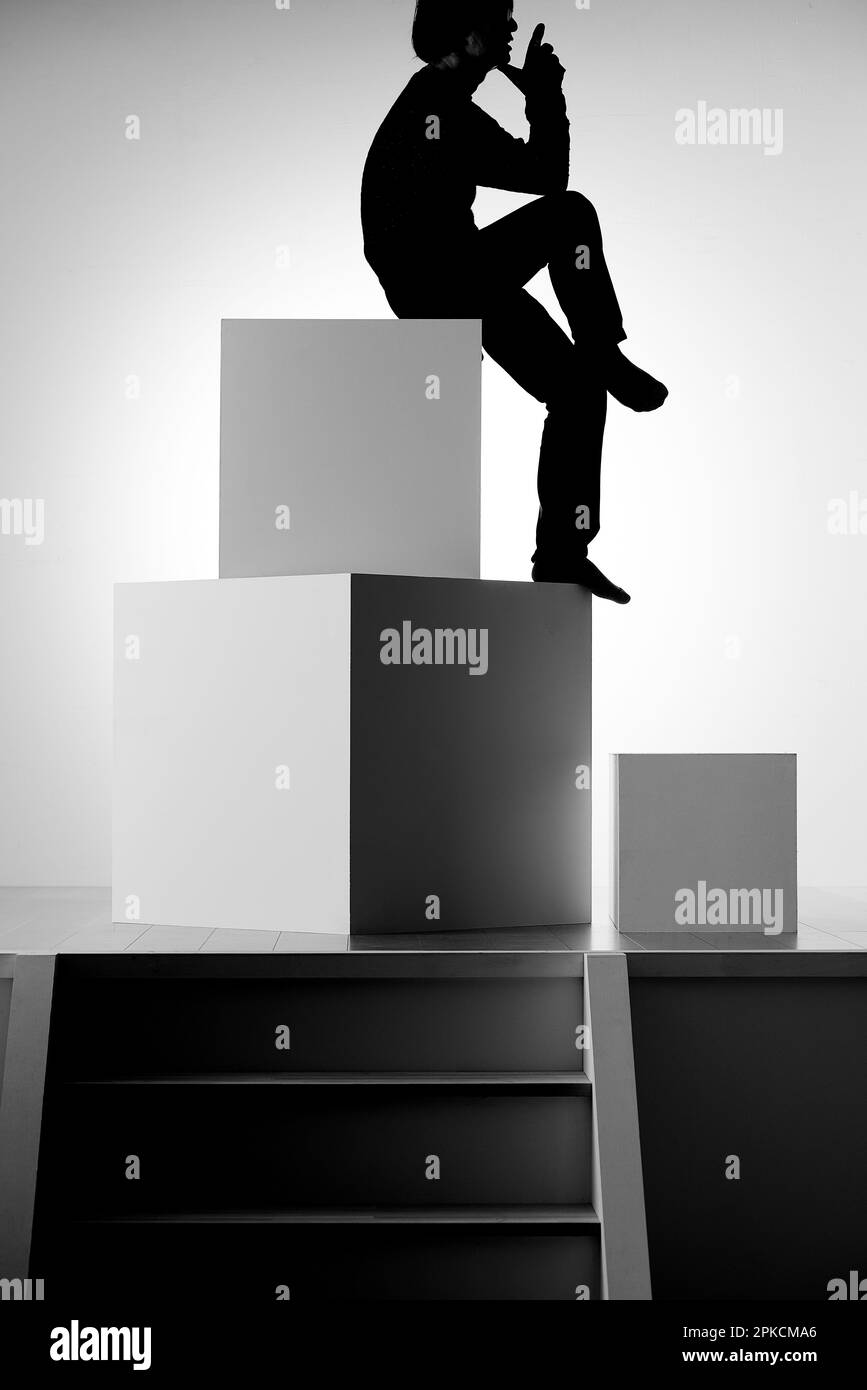 Figure sitting on object made by combination of squares Stock Photo - Alamy