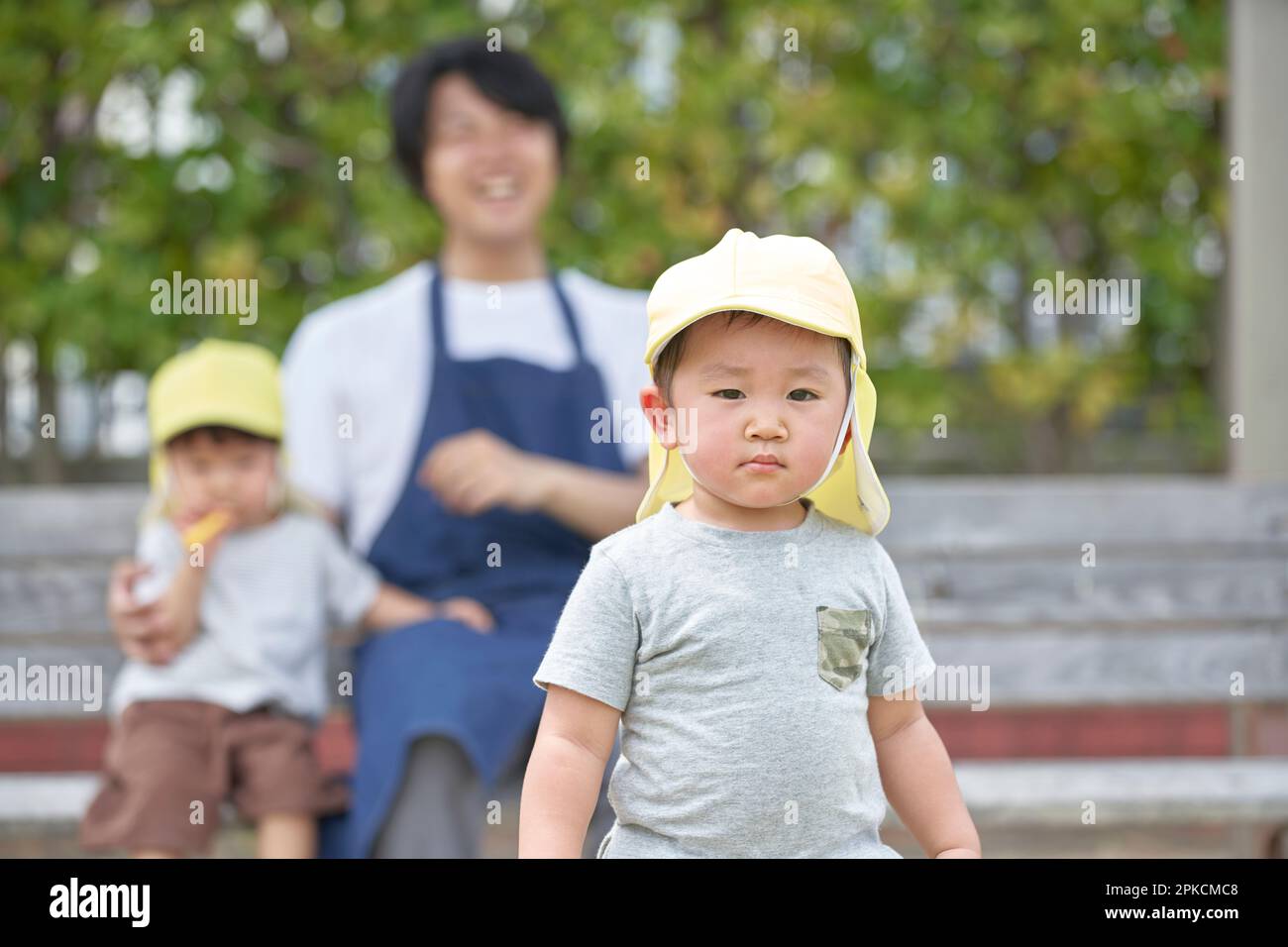 Male child care worker and children sitting on a bench Stock Photo - Alamy