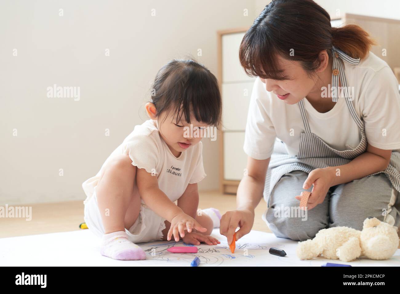 Child and female child care worker drawing on the floor Stock Photo - Alamy