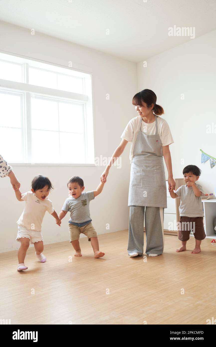 Female child care worker holding hands with children Stock Photo - Alamy