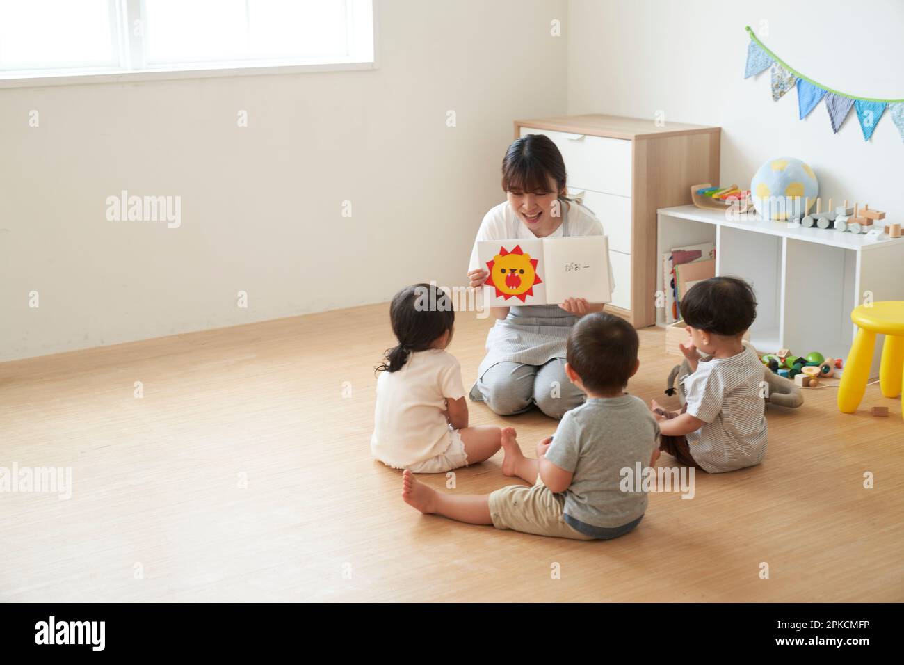 Female nursery school teacher reading a picture book to children Stock ...