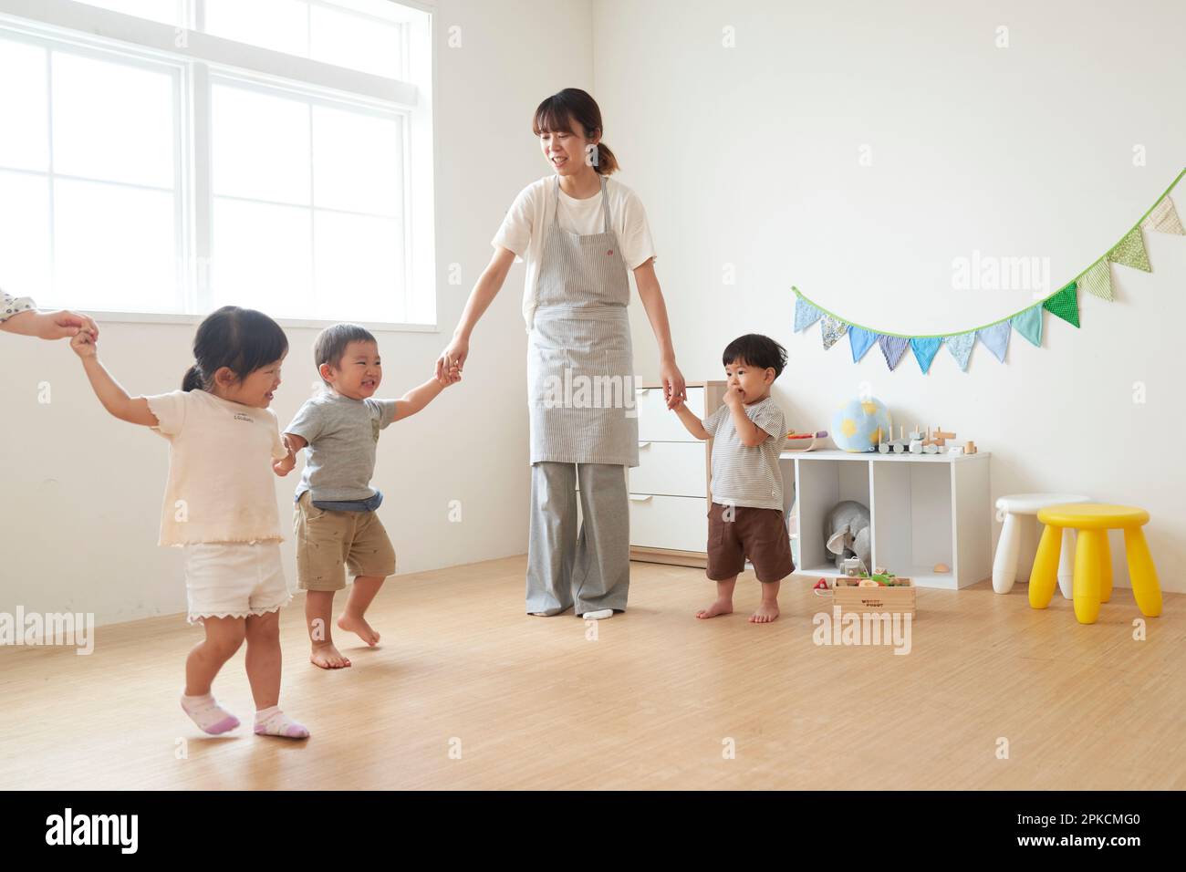 Female childcare worker holding hands with children Stock Photo - Alamy