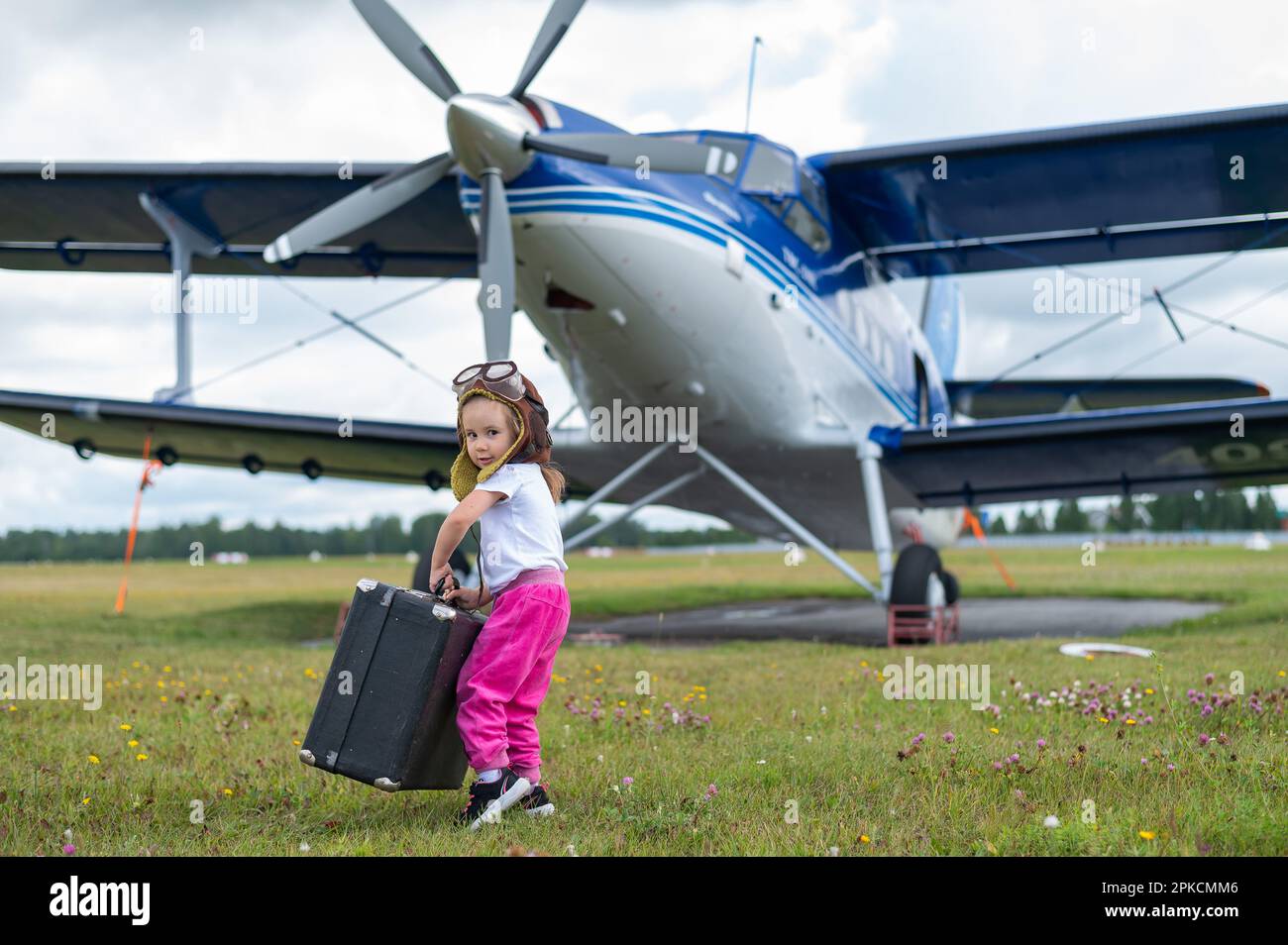 A cute little girl playing on the field by a four-seater private jet ...