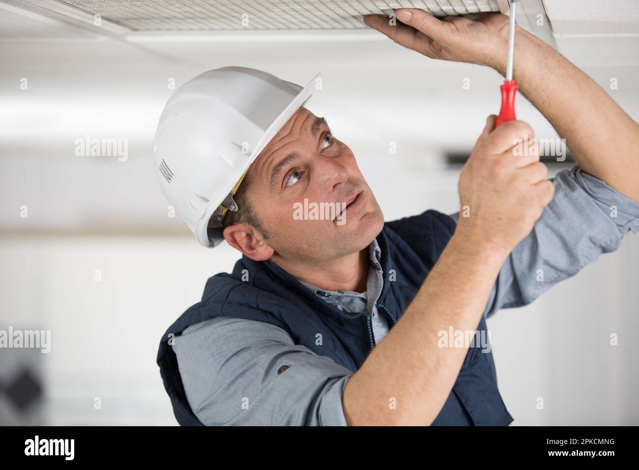 electrical engineer performs the installation of a ceiling lamp Stock ...