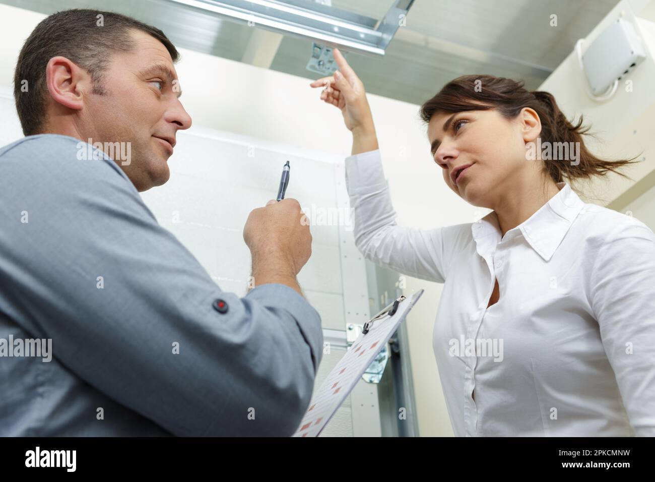 workers pointing at ceiling of a factory Stock Photo - Alamy