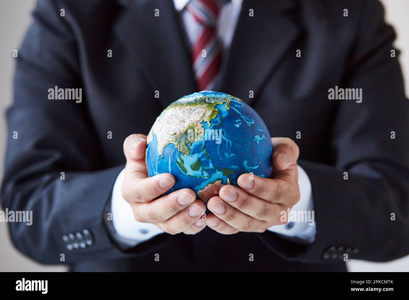 Man in suit holding earth object Stock Photo - Alamy