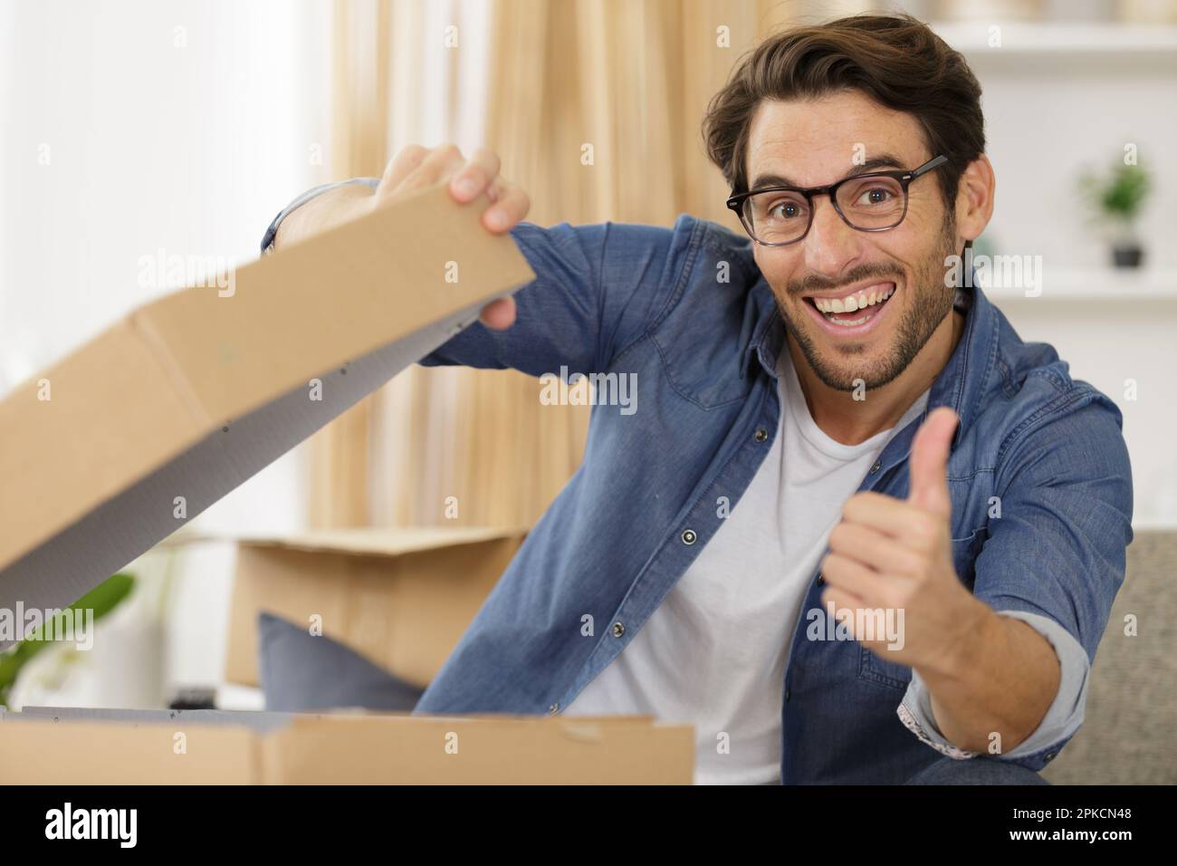 happy man opening parcel box at home showing thumb up Stock Photo - Alamy