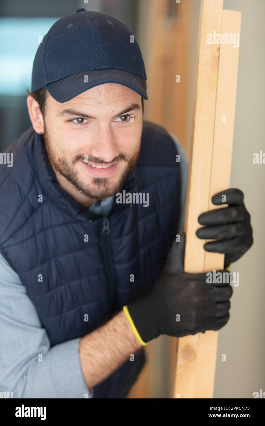 smiling carpenter holding wood planks Stock Photo - Alamy