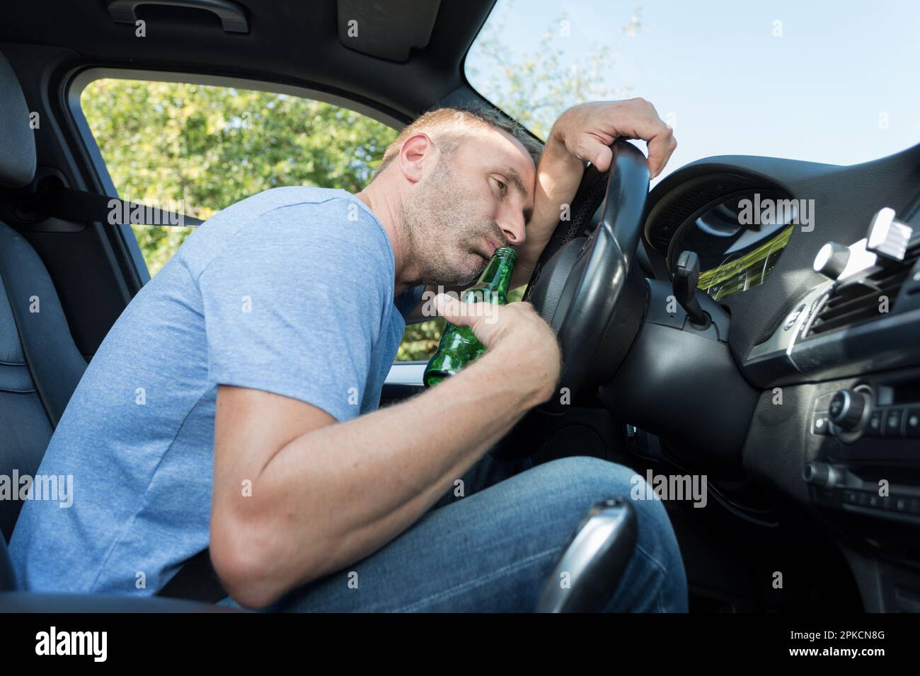 drunk man driving a car holding bottle beer Stock Photo - Alamy