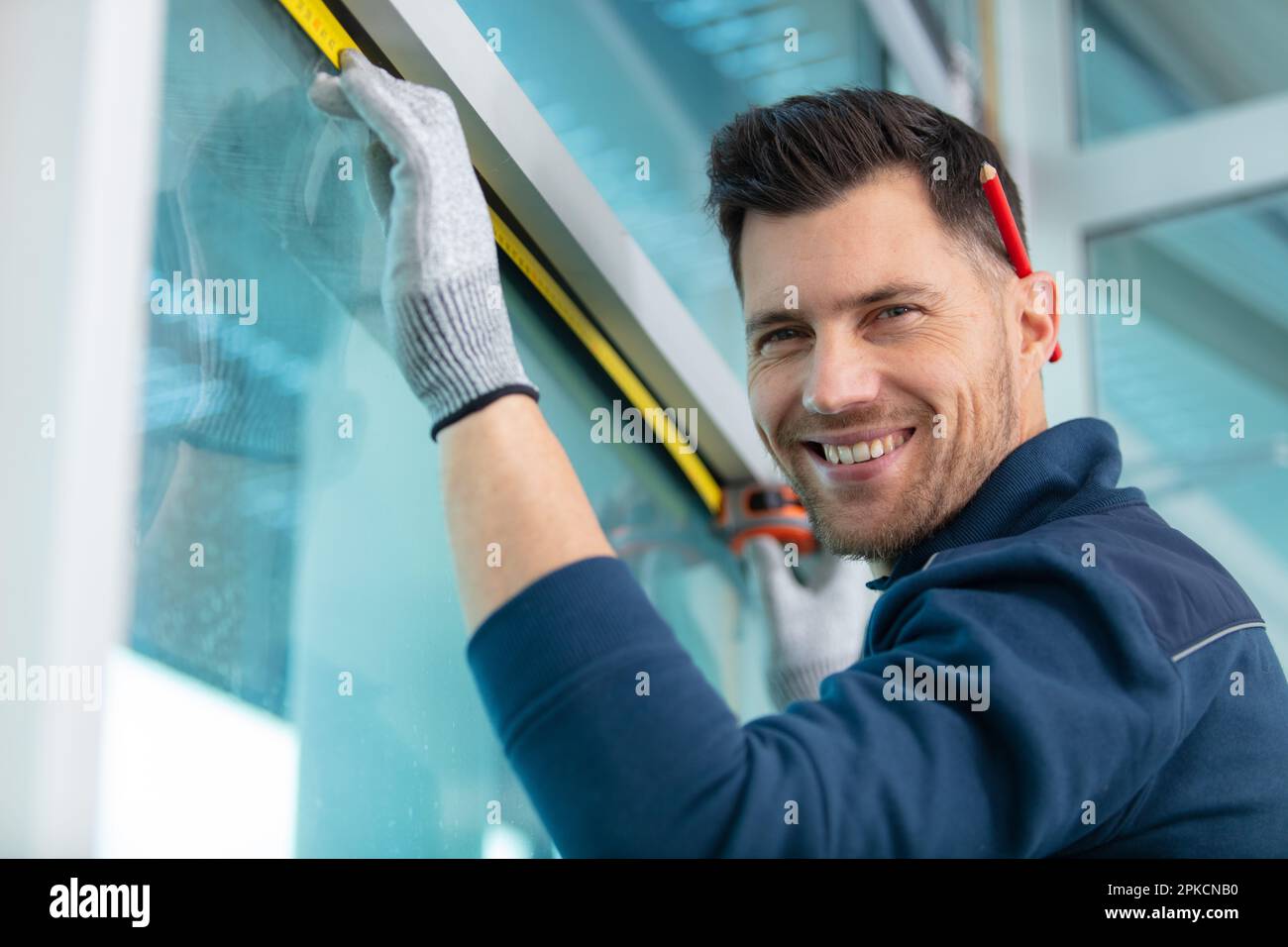 builder is measuring window using measure tape at construction site ...
