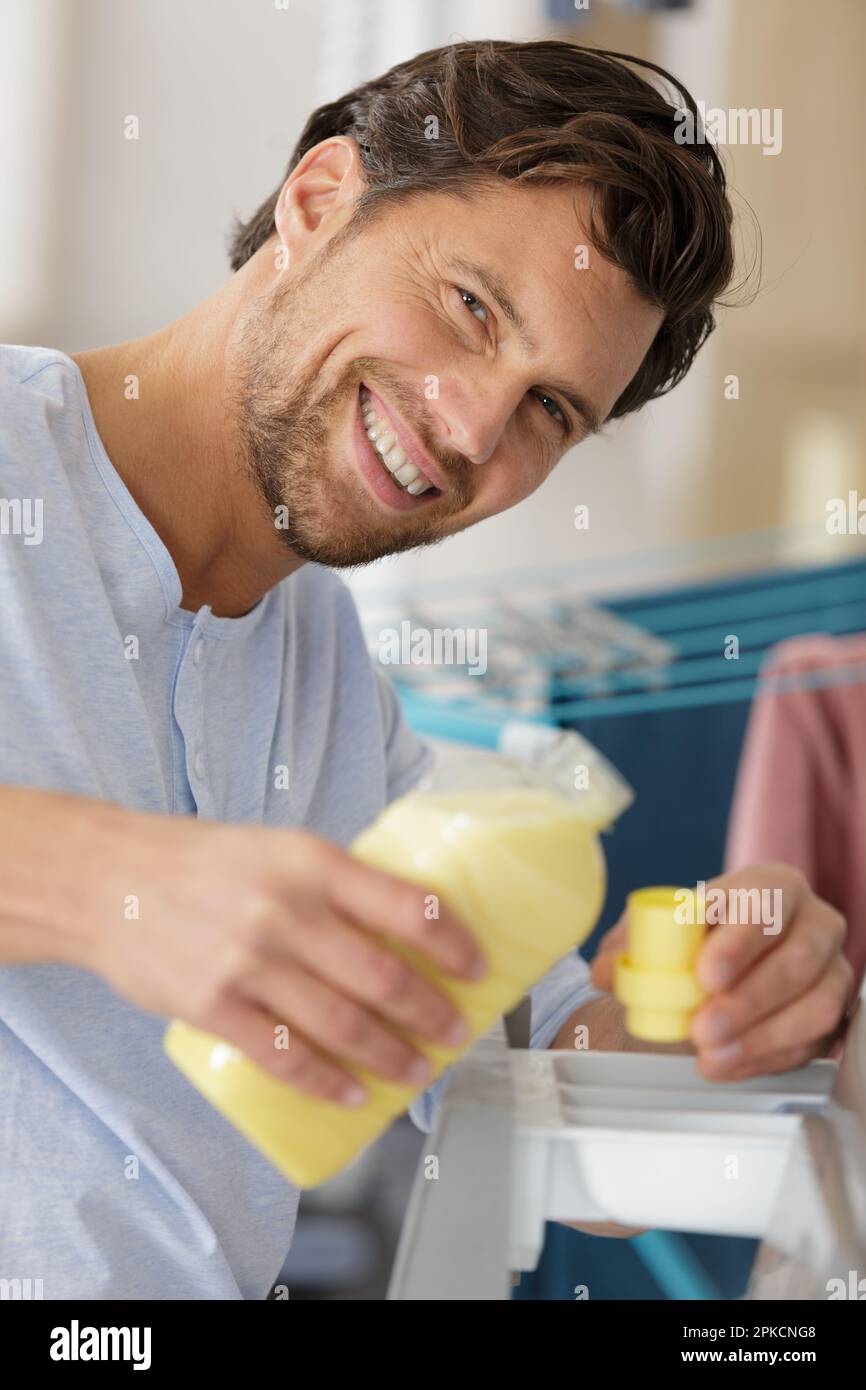 man pouring liquid laundry detergent in washing machine Stock Photo - Alamy