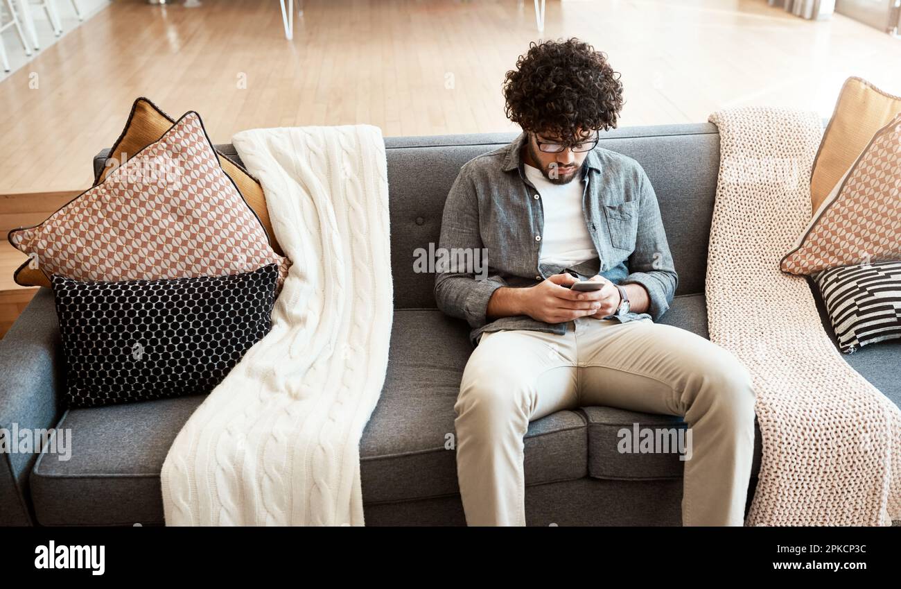 Its how I prefer to chill. a handsome young man using his cellphone ...