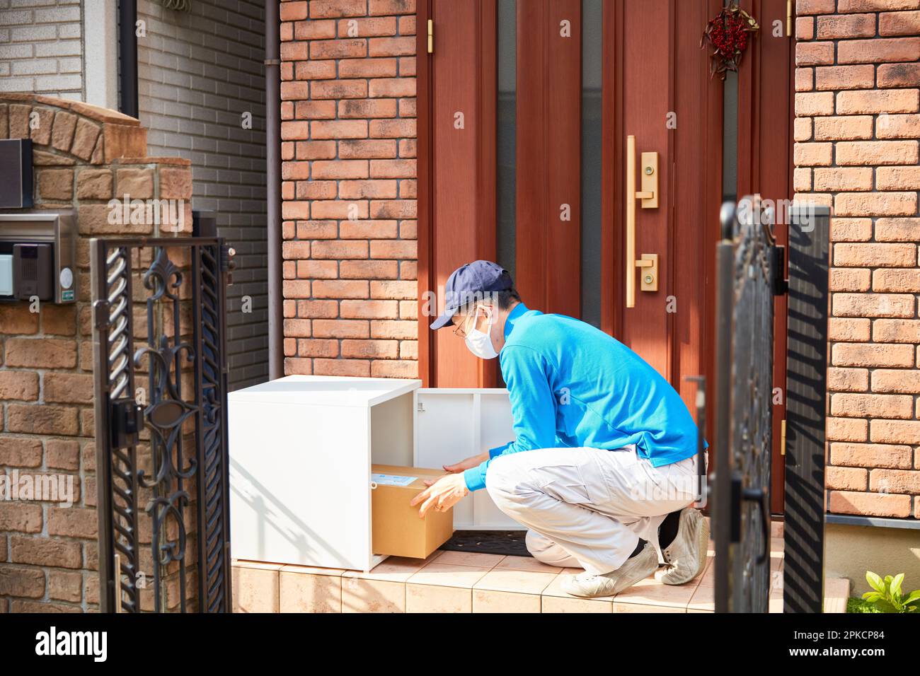 Man in work clothes putting delivery into delivery box Stock Photo - Alamy