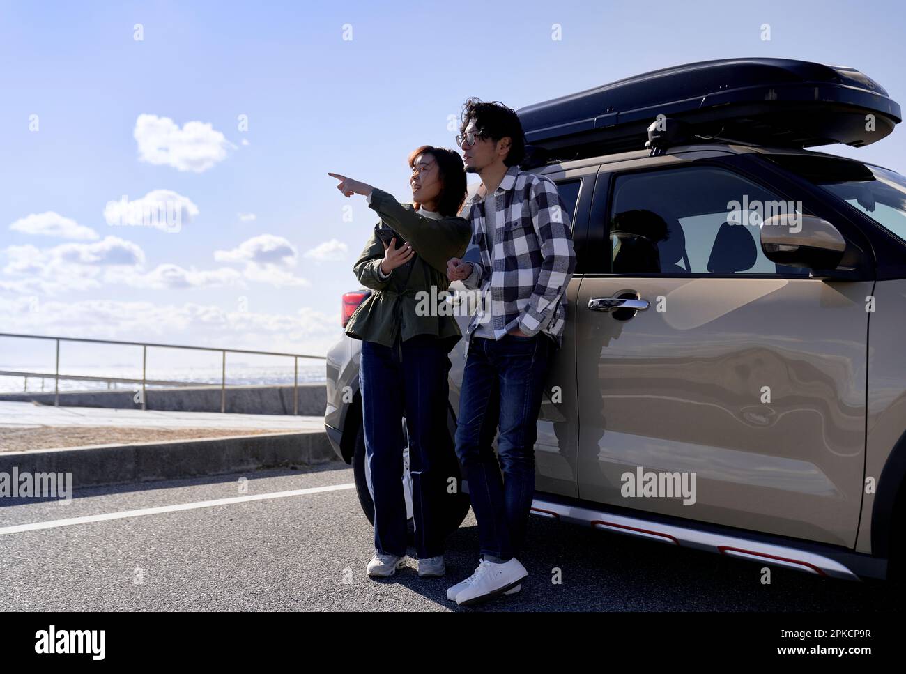 Man and woman pointing into the distance next to a car Stock Photo - Alamy