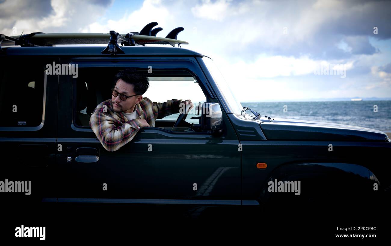 Man leaning out of car window looking backward Stock Photo - Alamy