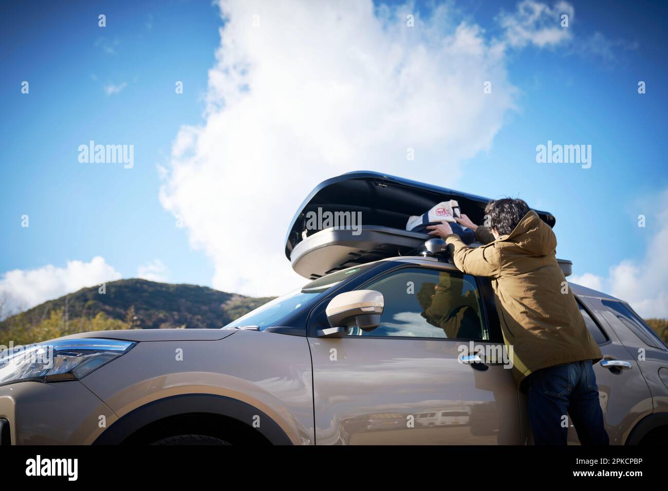 Man putting luggage in carry-on box on top of car Stock Photo - Alamy