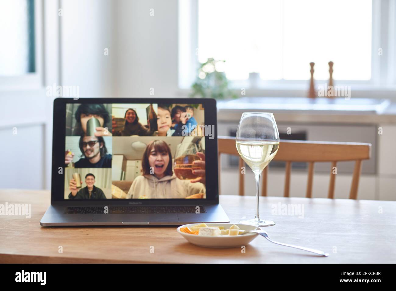 Screen of a computer, white wine and snacks while drinking remotely ...