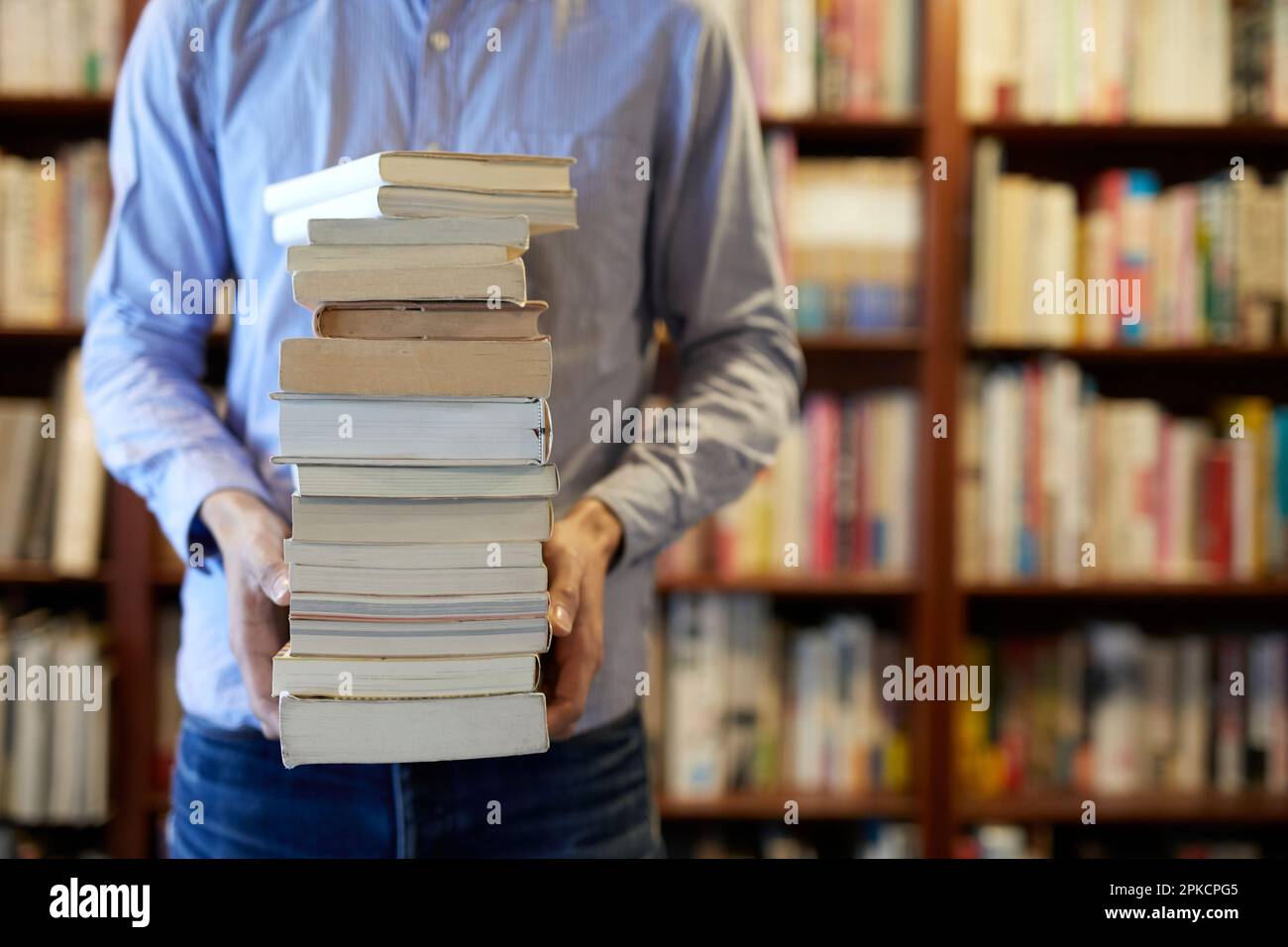 Man carrying a stack of books Stock Photo - Alamy