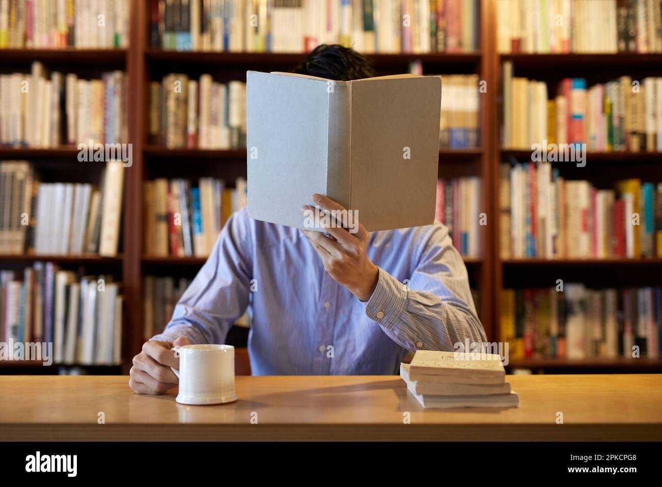 Man opening a book in front of his face Stock Photo - Alamy