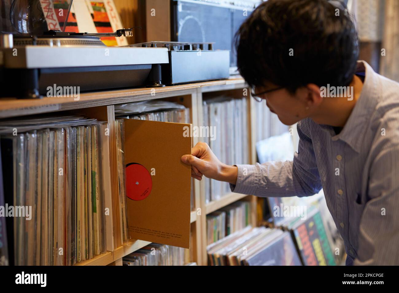 Man pulling out a record from the shelf Stock Photo - Alamy
