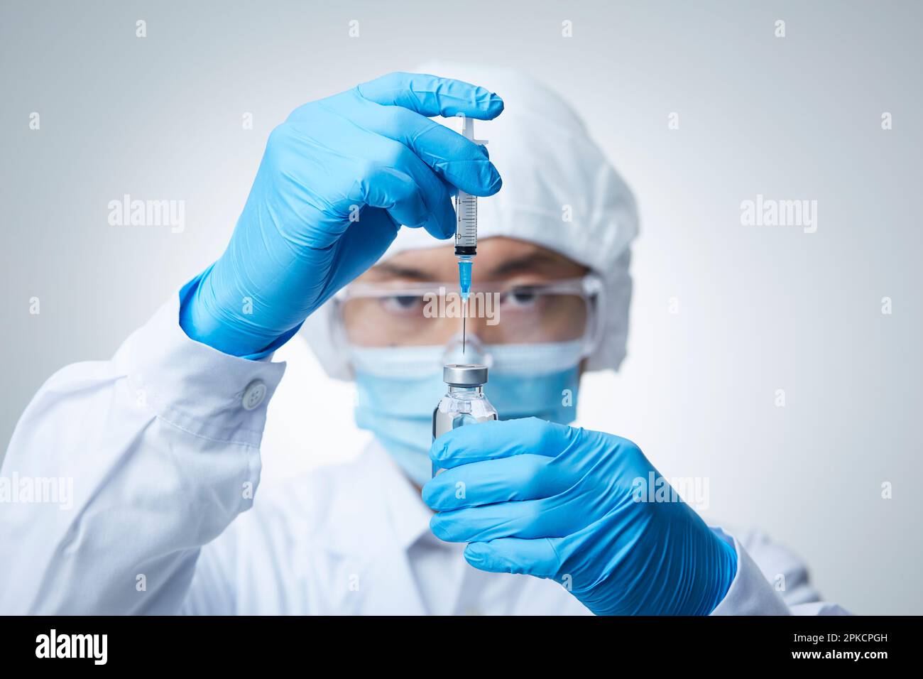 Man in white inserting a syringe into a bottle Stock Photo - Alamy