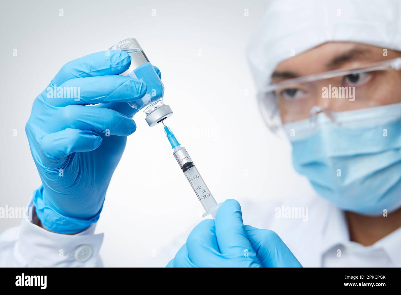 Man in lab coat inserting syringe into bottle Stock Photo - Alamy