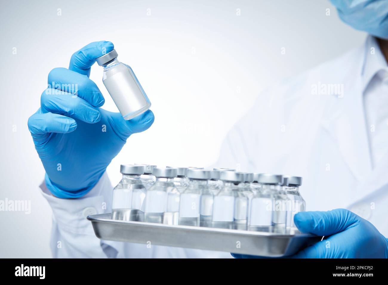 Man in lab coat selecting one of many vials Stock Photo - Alamy