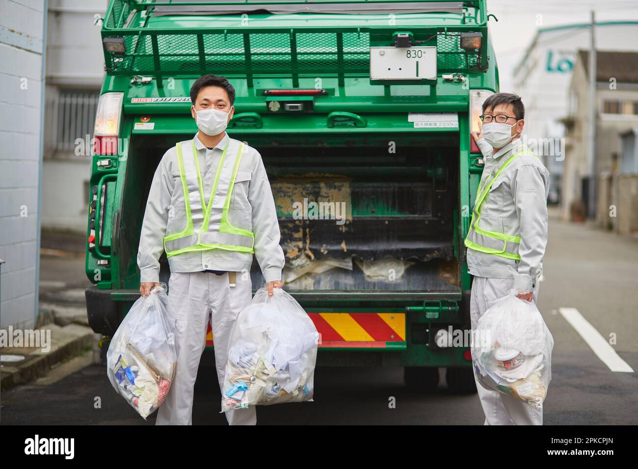 Packer truck and male worker collecting garbage Stock Photo - Alamy