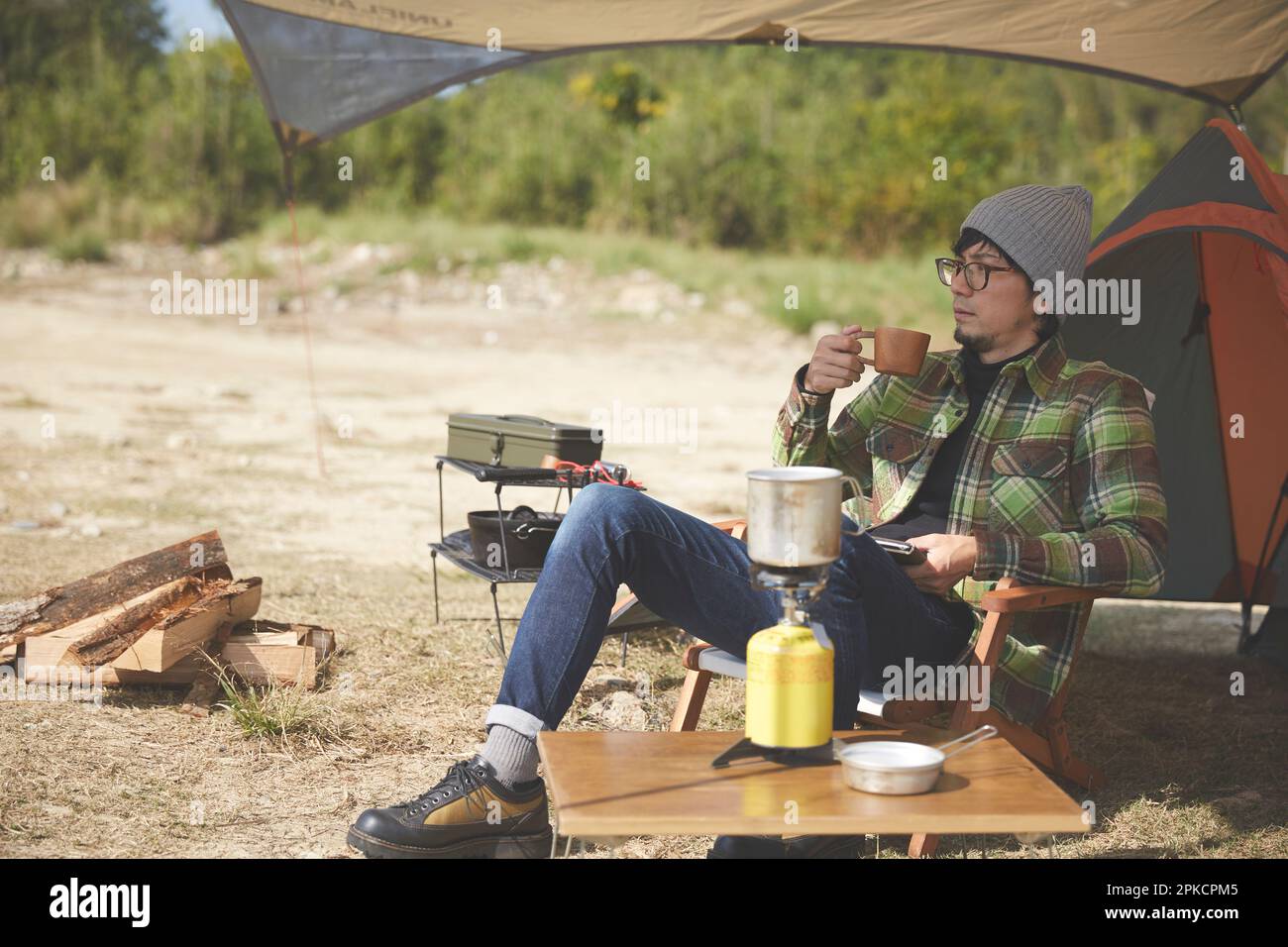 Man sitting in front of tent drinking coffee Stock Photo - Alamy