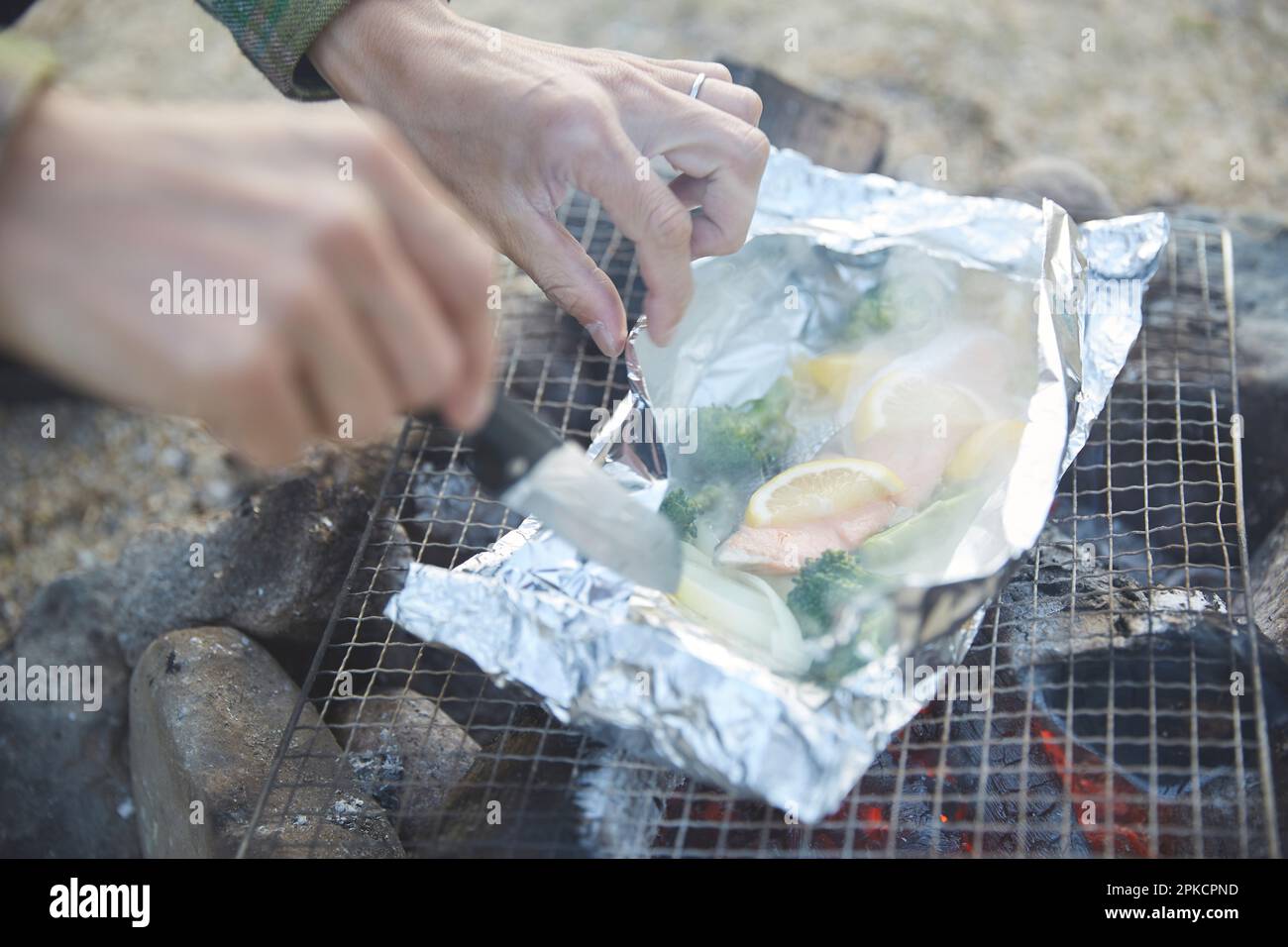 Man's hand opening aluminum foil for roasting foil Stock Photo - Alamy