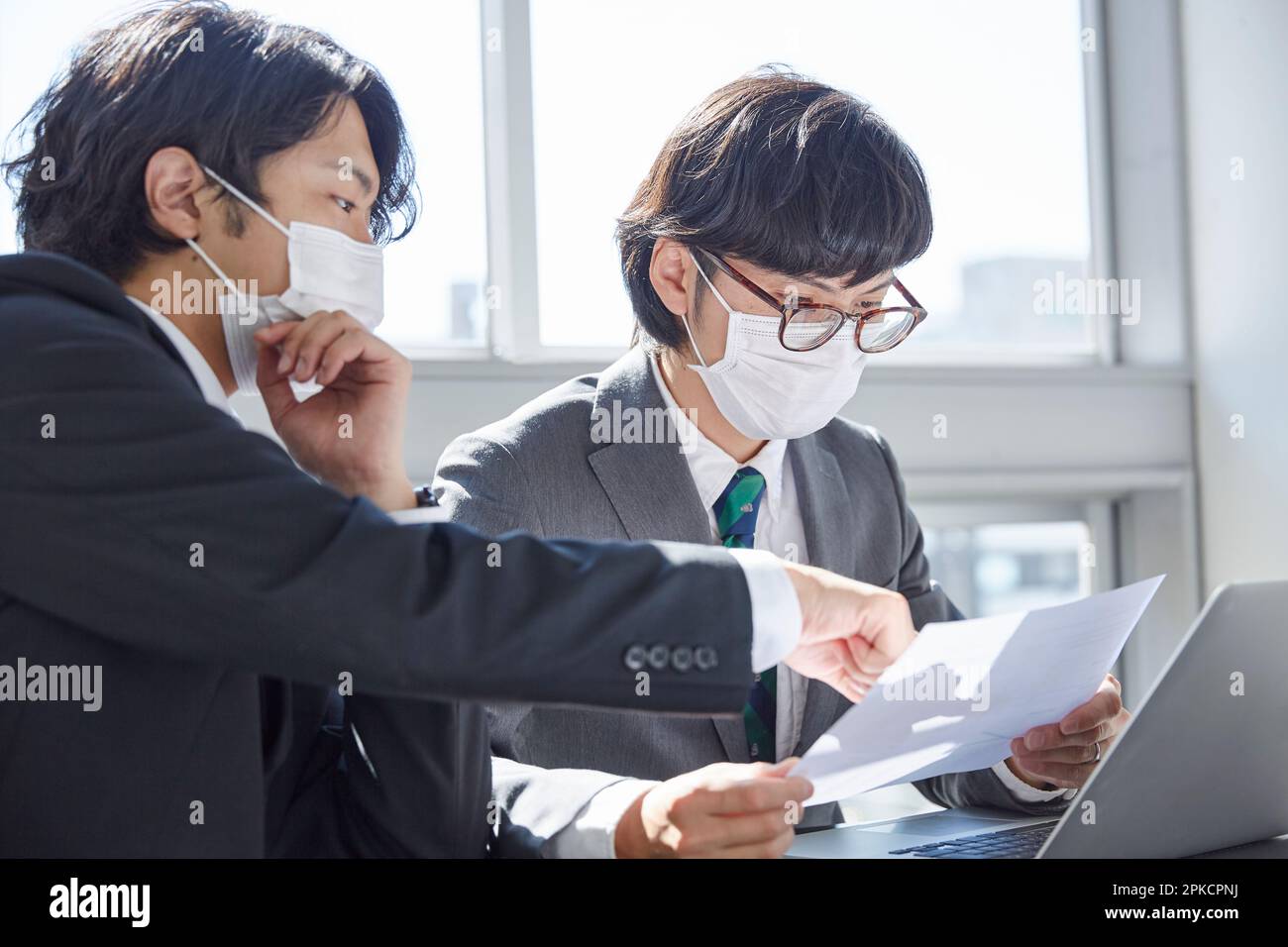 Two men talking in office wearing masks Stock Photo - Alamy