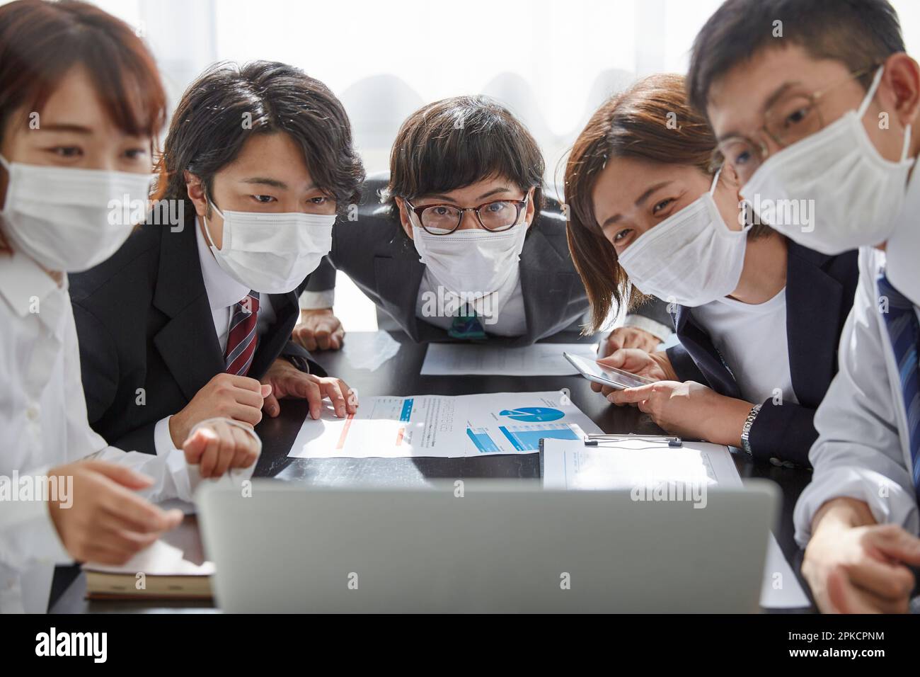 Company employee who has a remote meeting in his office wearing a mask ...