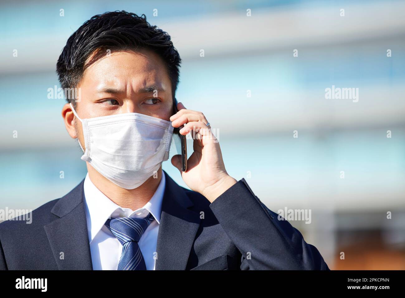 Man in suit making a phone call wearing a mask in an office area Stock ...