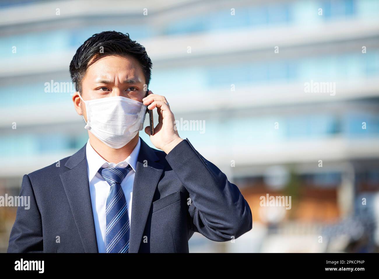 Man in suit making a phone call wearing a mask in an office area Stock ...