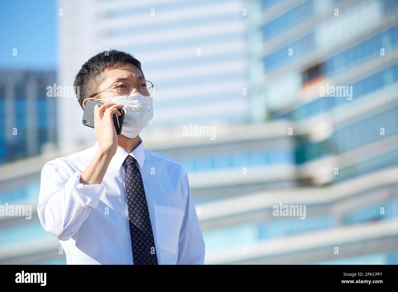 Man in suit making a phone call wearing a mask in an office block Stock ...