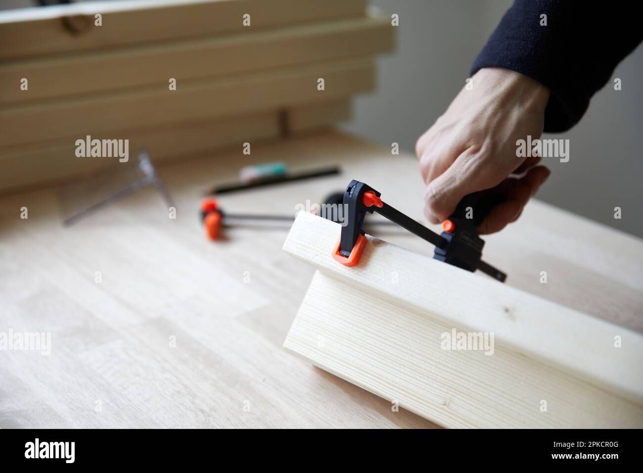 A man fastening a square piece of wood with an F-shaped clamp Stock ...