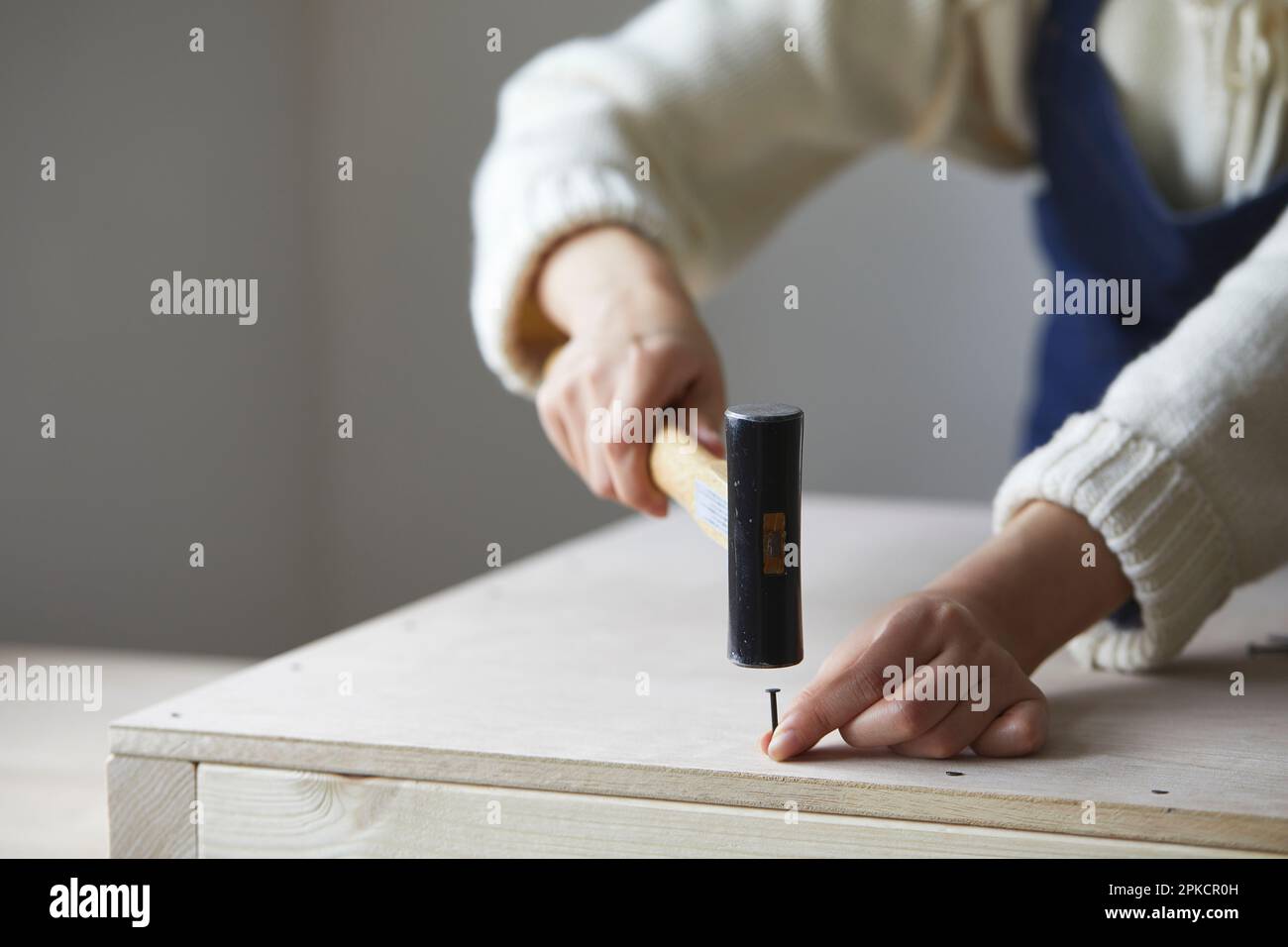 A hand hammering a nail into a piece of wood Stock Photo - Alamy