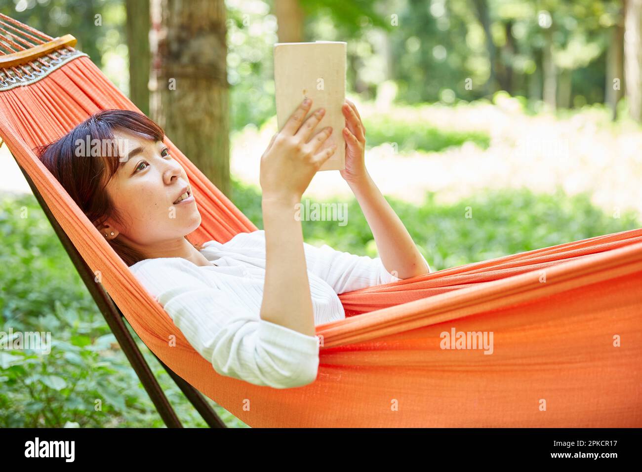Woman reading a book lying in a hammock Stock Photo - Alamy